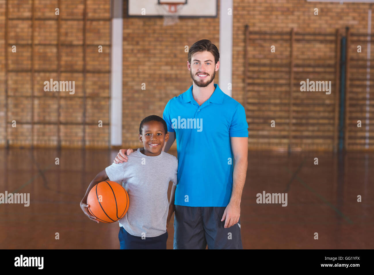 Portrait of sports teacher standing with his student in basketball ...