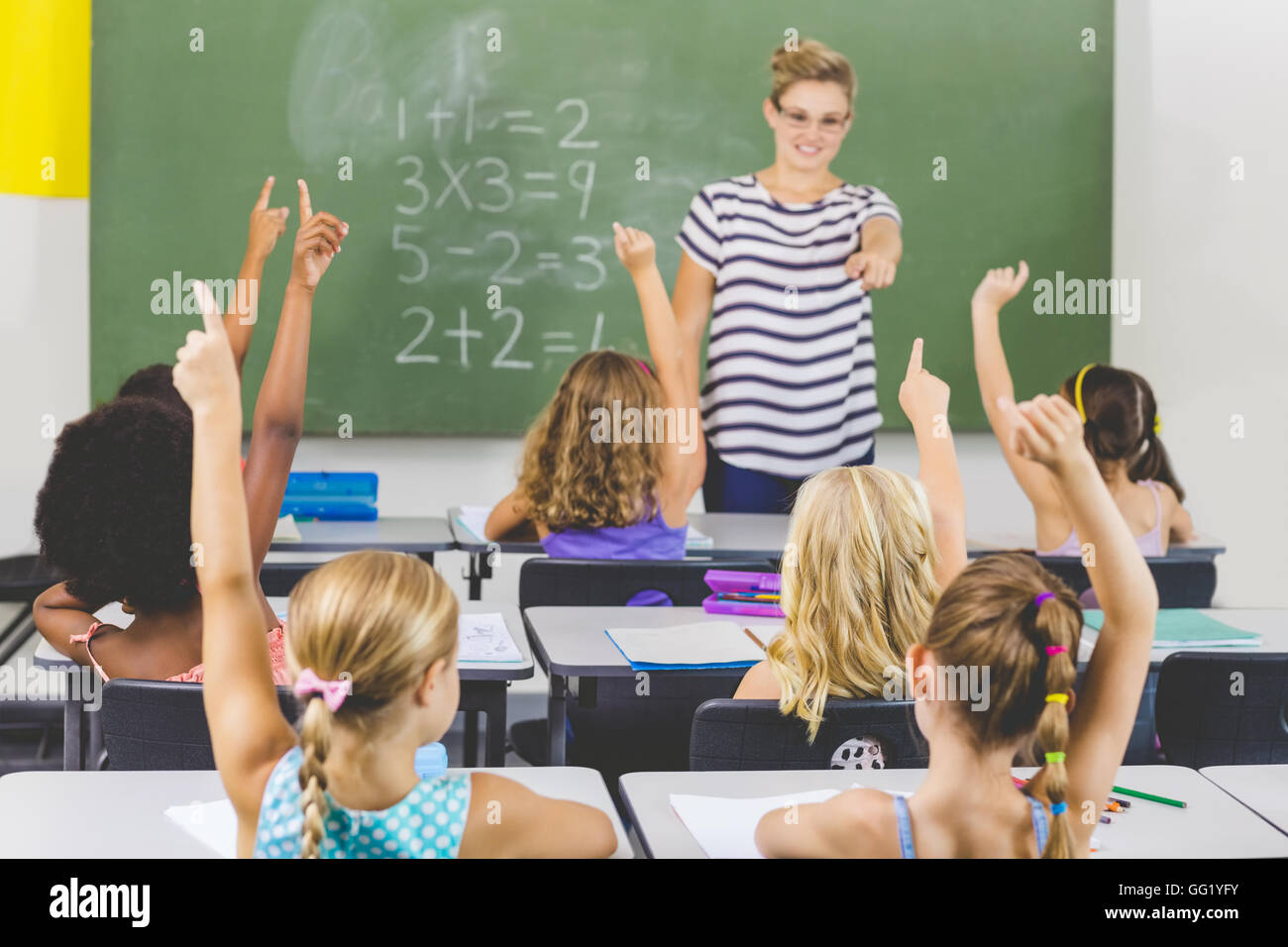 School kids raising hand in classroom Stock Photo - Alamy
