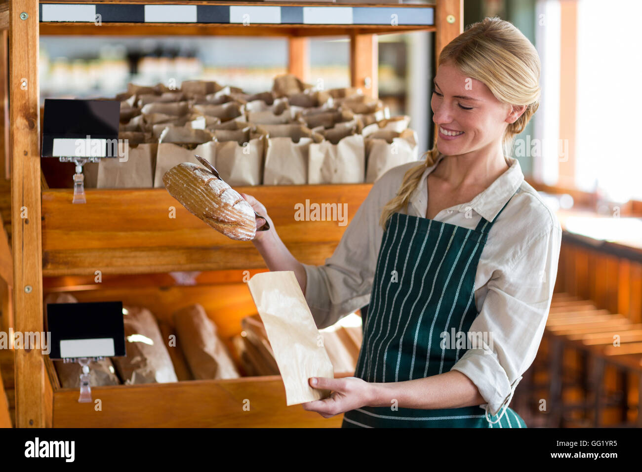 Female staff packing a bread in paper bag Stock Photo - Alamy