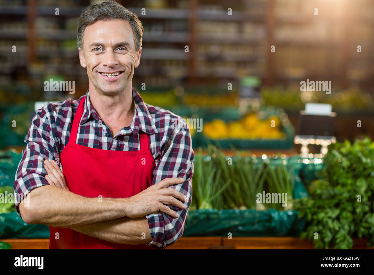 Smiling male staff standing with arms crossed in organic section Stock ...