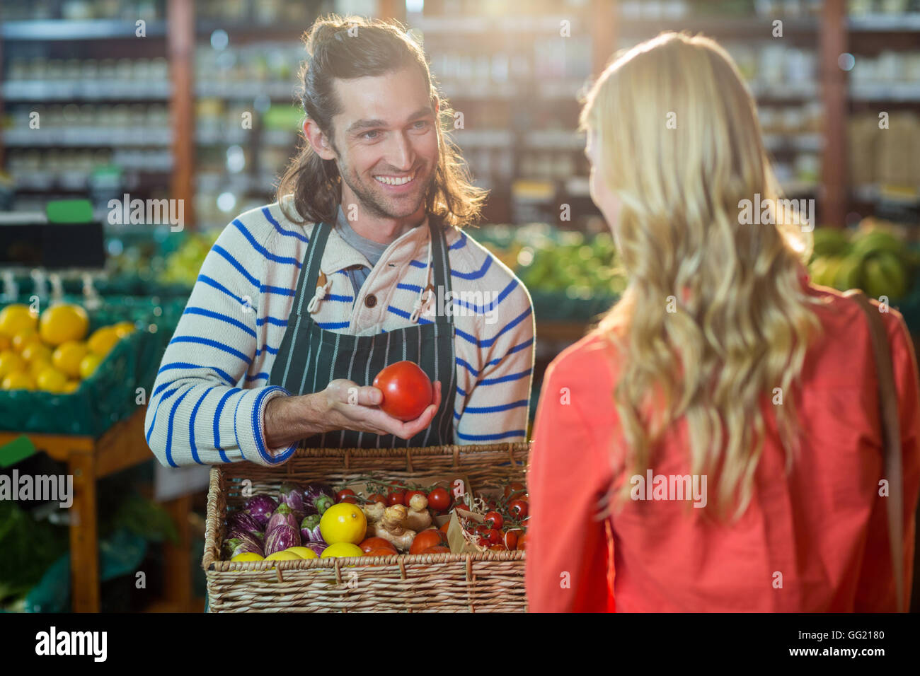 Male staff assisting woman in selecting fresh vegetables Stock Photo ...