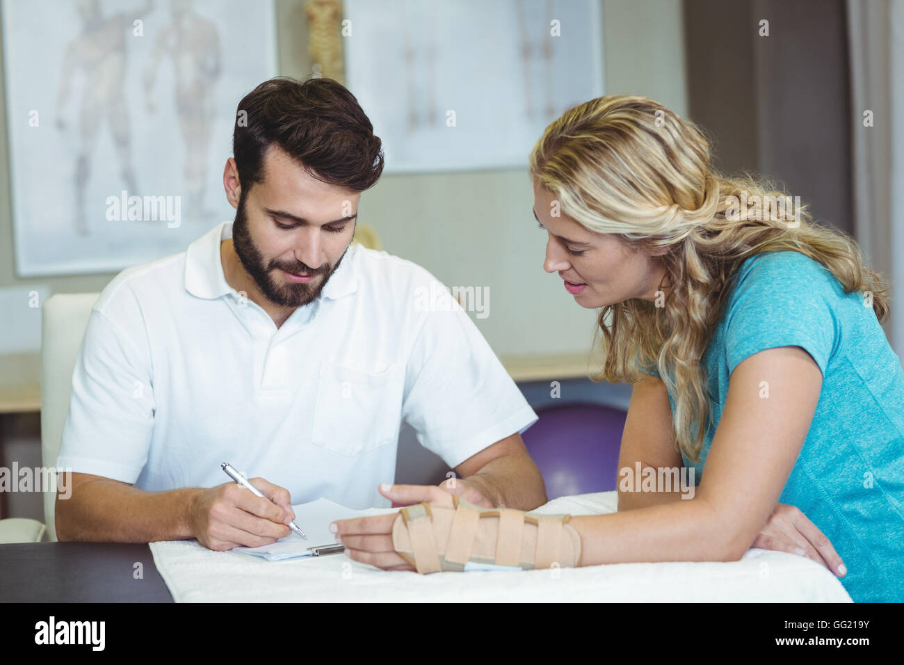 Physiotherapist writing report next to the patient Stock Photo - Alamy