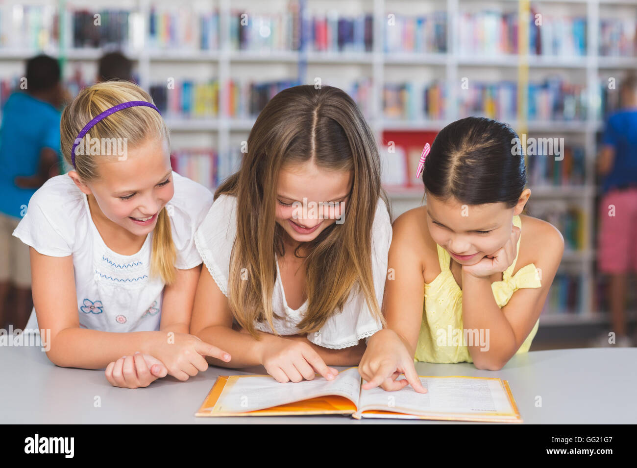 School kids reading book together in library Stock Photo - Alamy