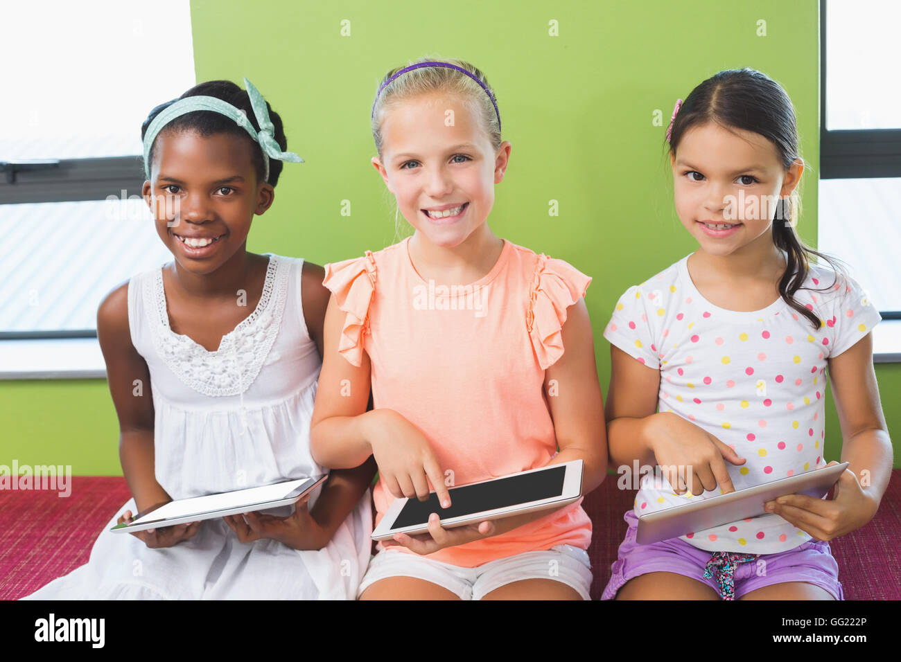 Schoolgirls using digital tablet in library Stock Photo - Alamy