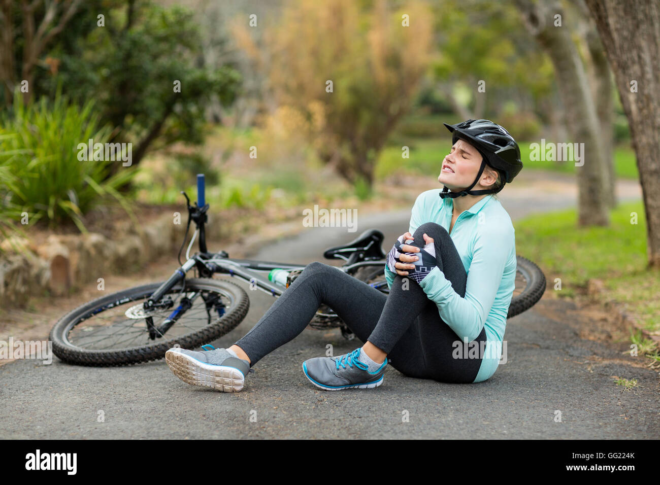 Female cyclist in pain holding her injured leg Stock Photo - Alamy