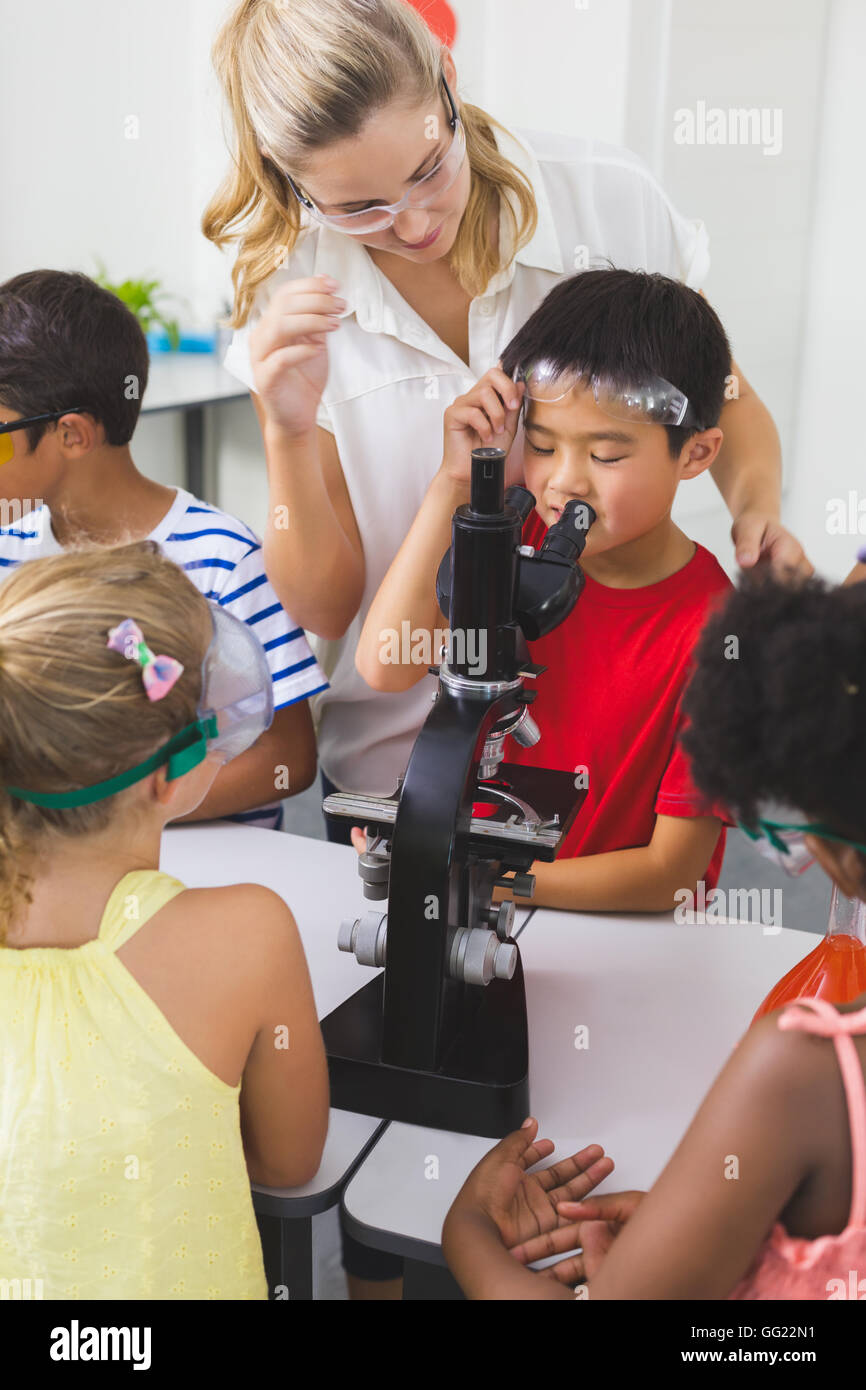 Teacher assisting kids in laboratory Stock Photo - Alamy