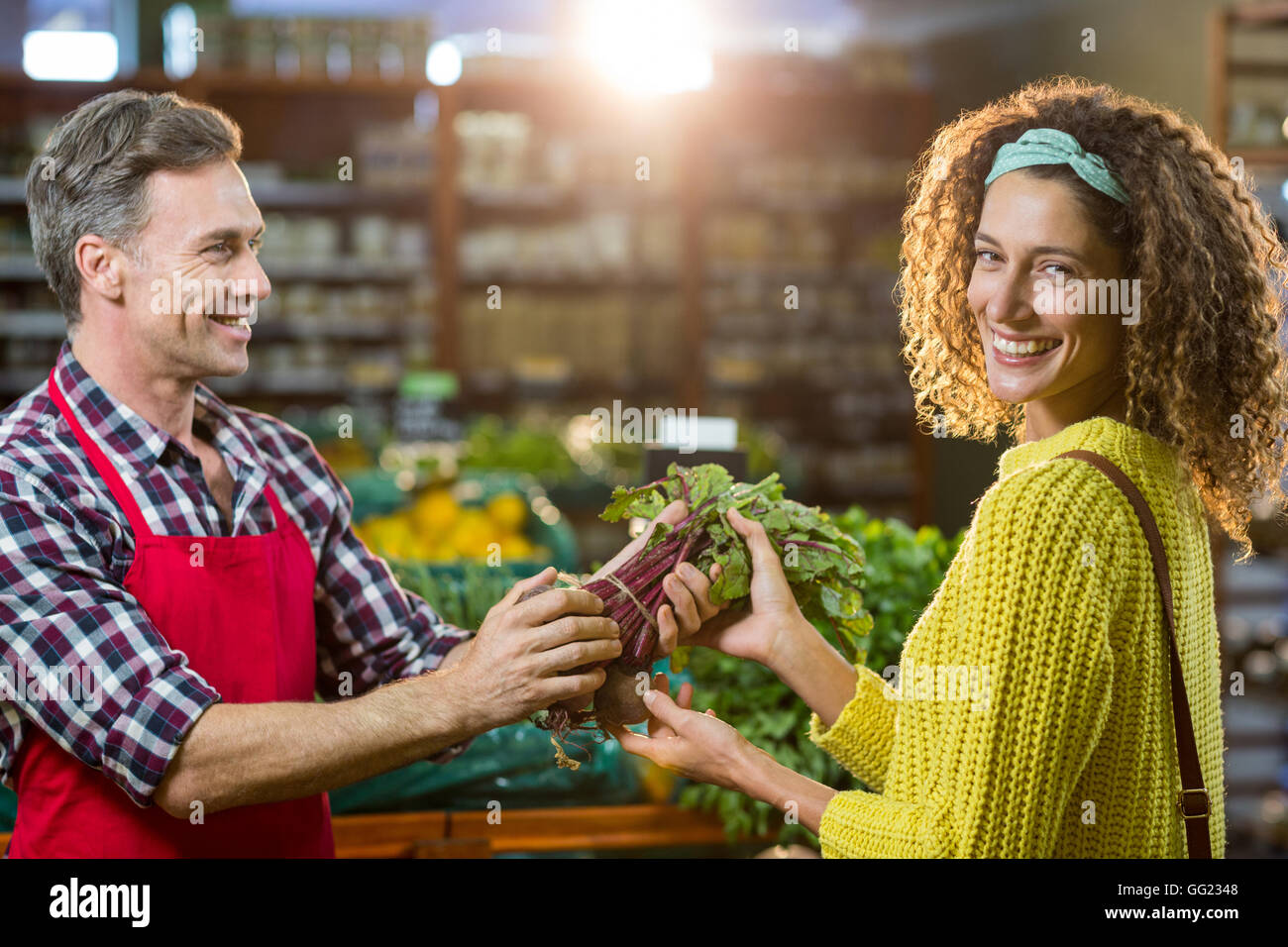 Smiling male staff assisting a woman with grocery shopping Stock Photo ...