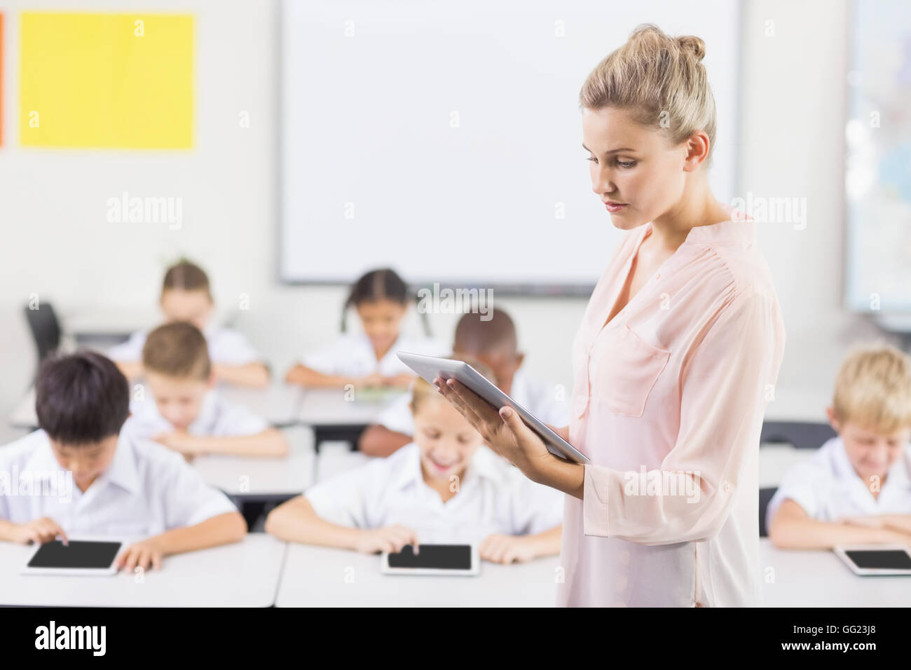 Teacher teaching kids on digital tablet Stock Photo - Alamy