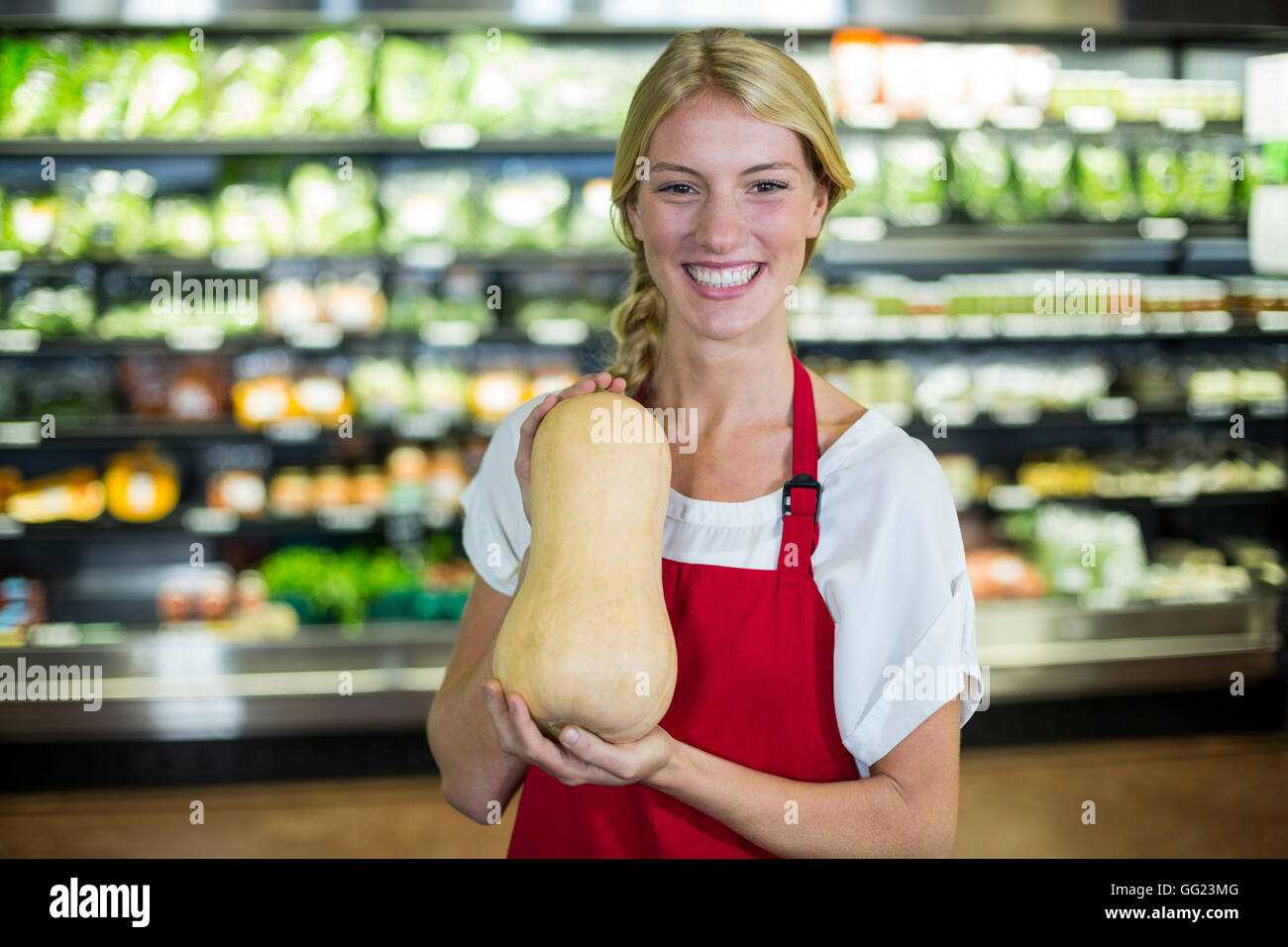 Smiling female staff holding a vegetable in organic section Stock Photo ...