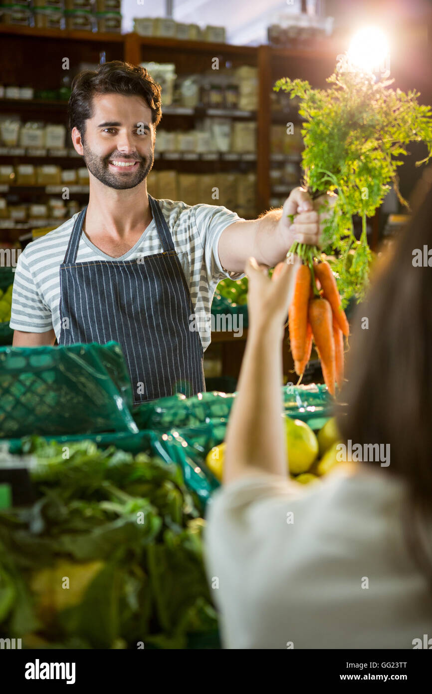 Smiling male staff assisting a woman with grocery shopping Stock Photo ...
