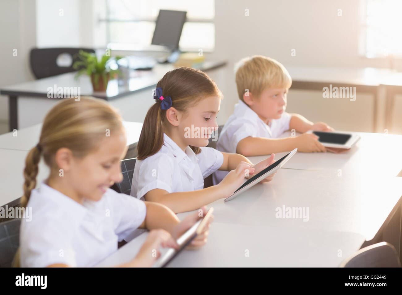 School kids using digital tablet in classroom Stock Photo - Alamy