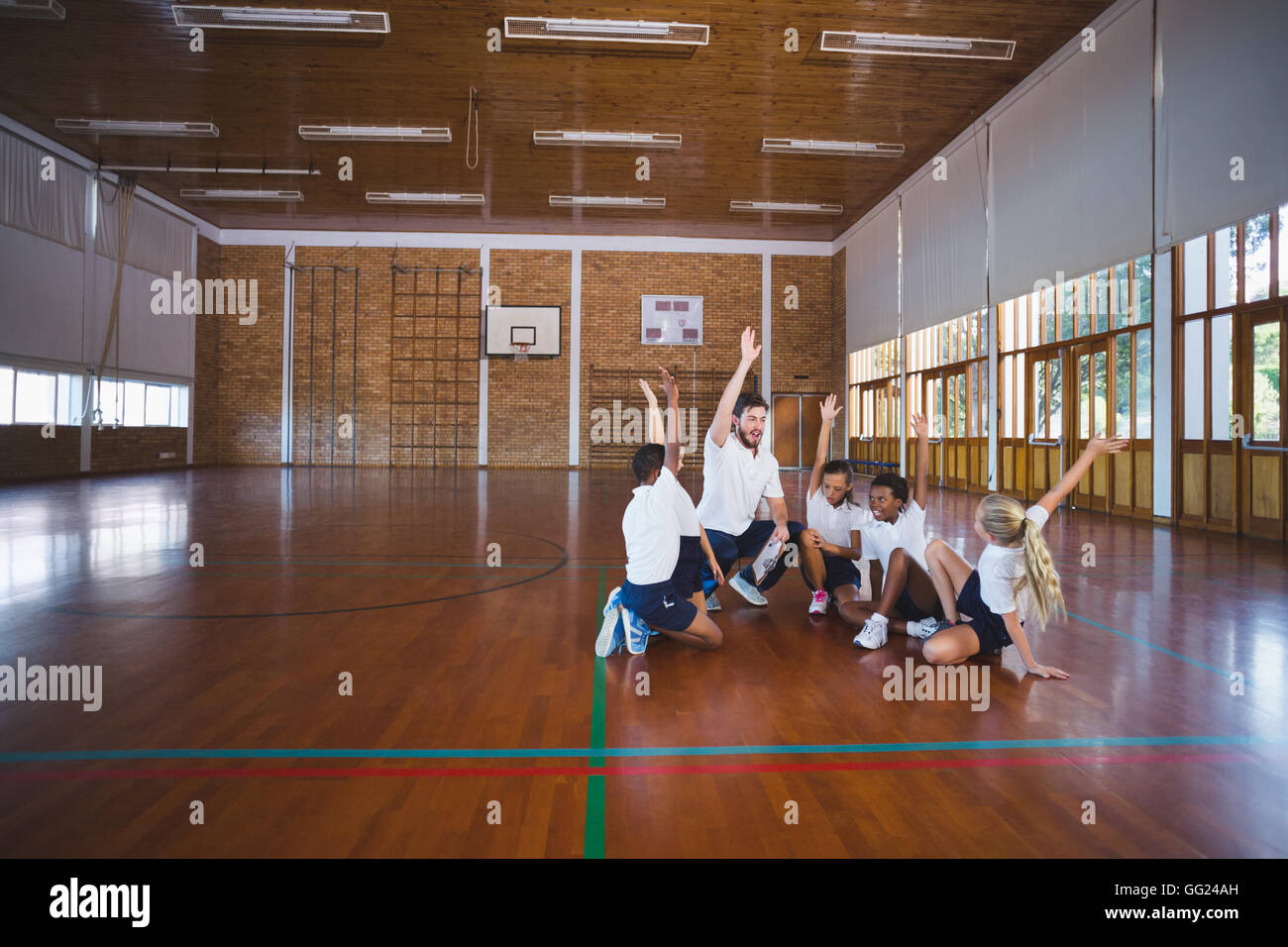 Sports teacher and school kids playing in basketball court Stock Photo ...
