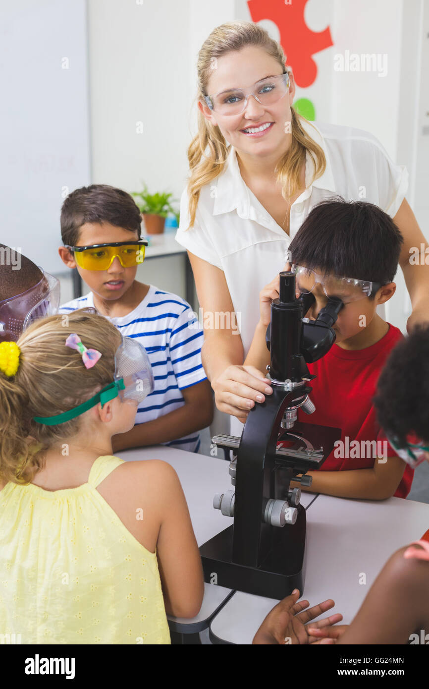 Teacher assisting kids in laboratory Stock Photo - Alamy