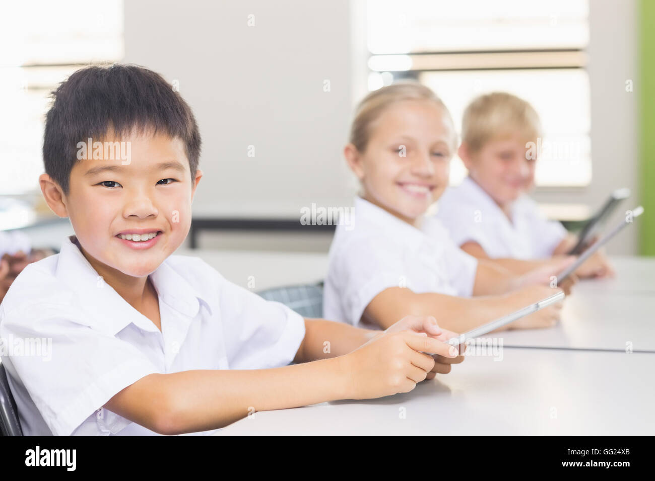Kids using digital tablet in classroom Stock Photo - Alamy