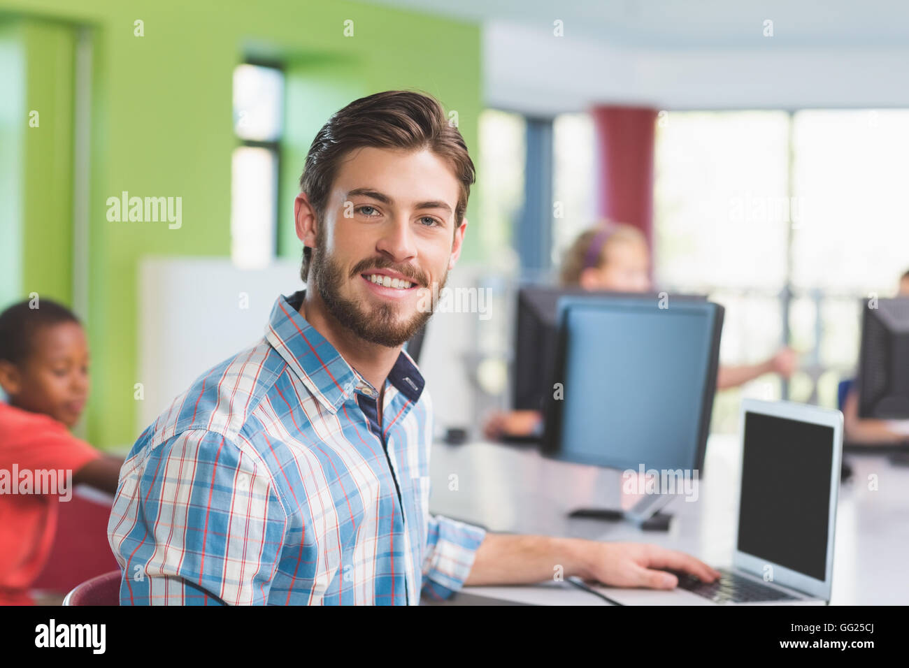 Teacher using laptop in classroom Stock Photo - Alamy