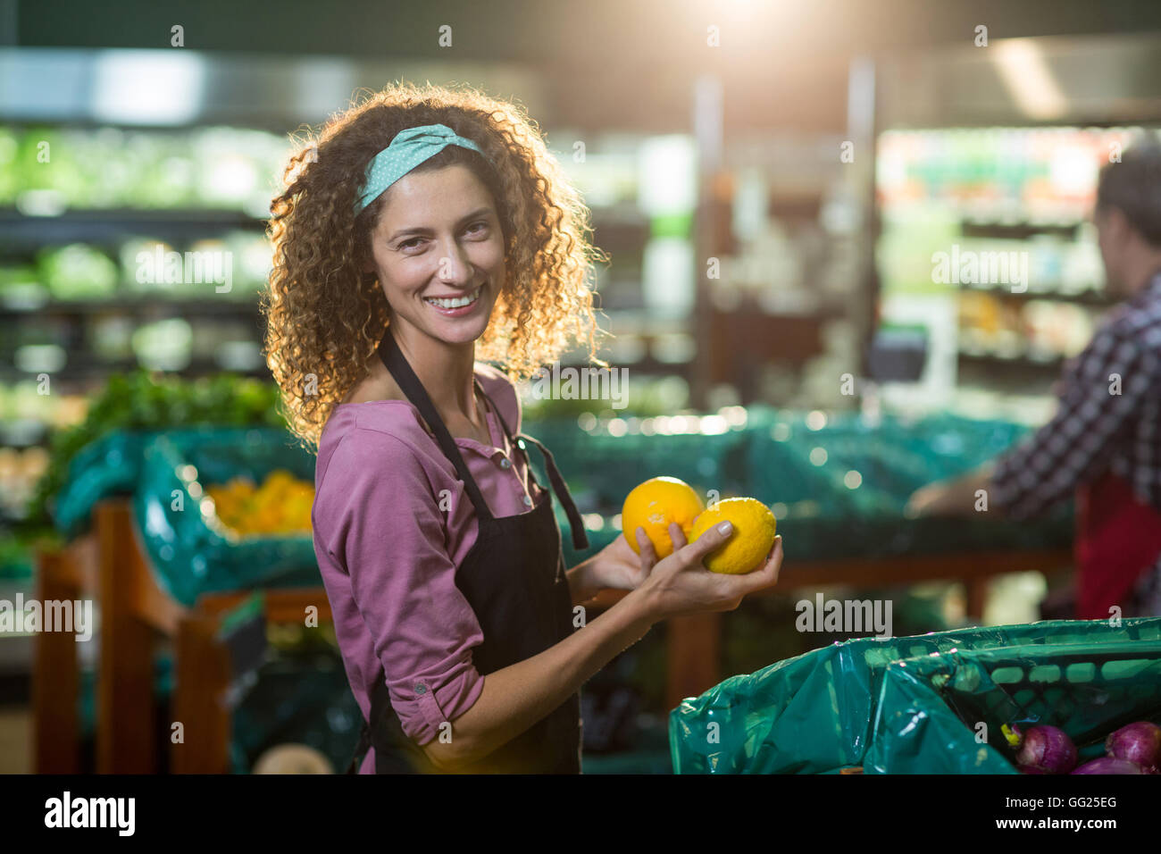 Smiling female staff holding fruits in organic section Stock Photo - Alamy