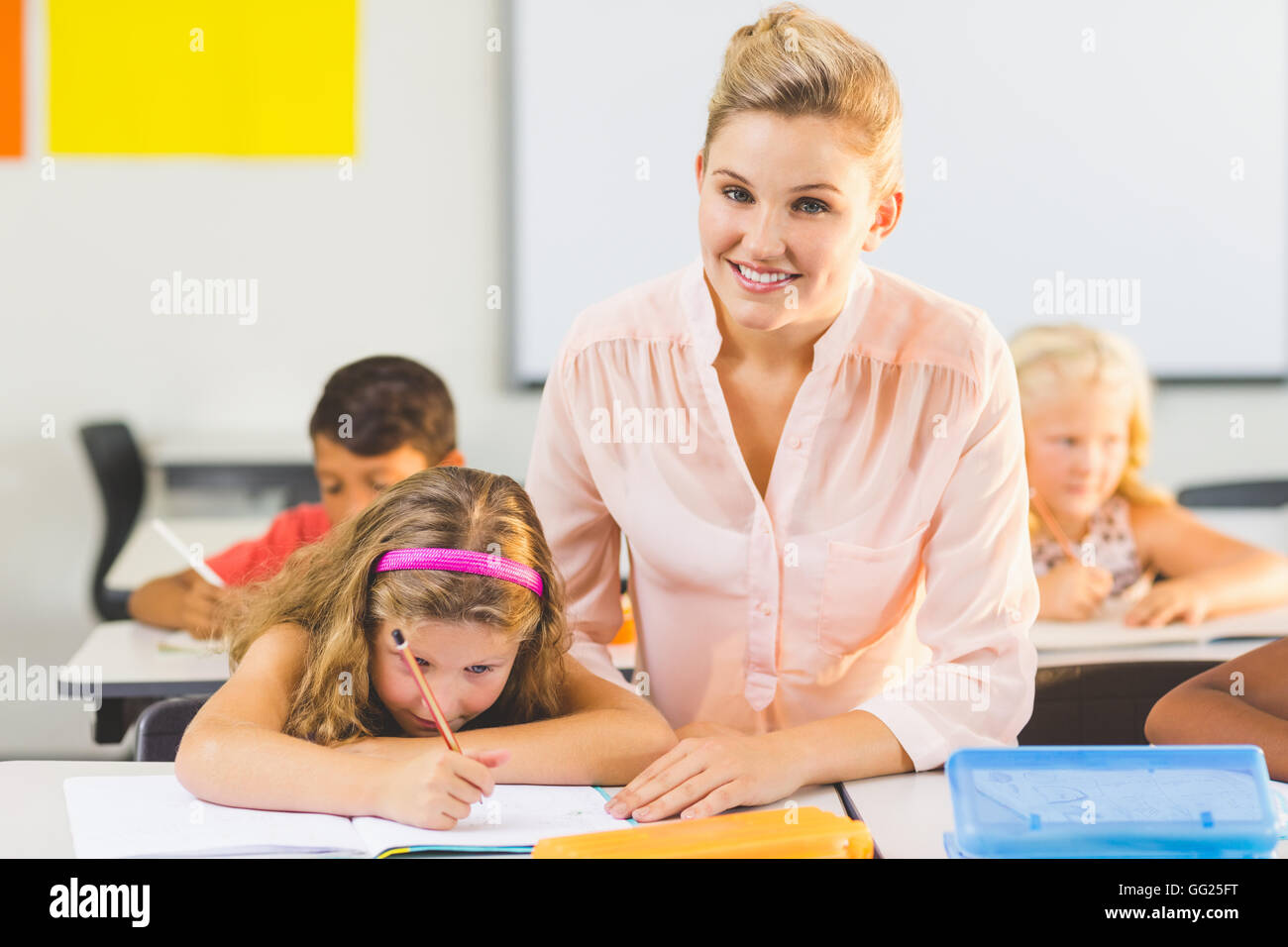 Teacher helping kids with their homework in classroom Stock Photo - Alamy