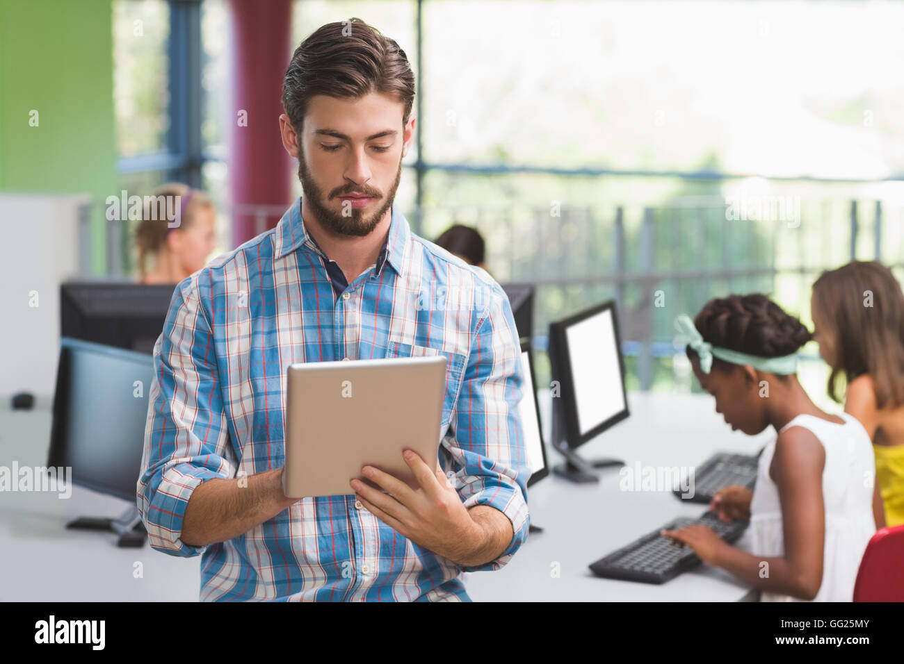 Teacher using digital tablet in classroom Stock Photo - Alamy