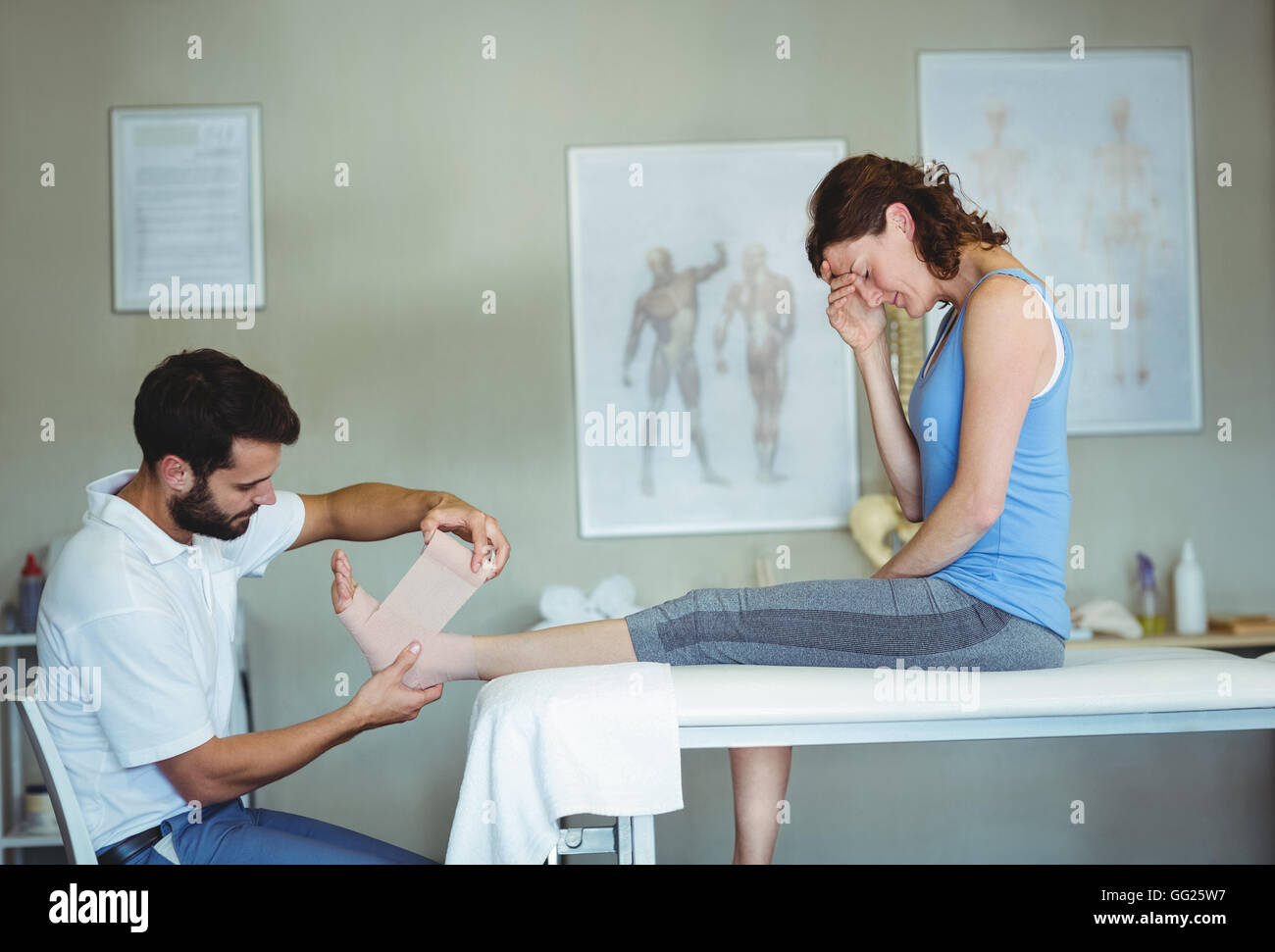 Physiotherapist putting bandage on injured feet of patient Stock Photo ...