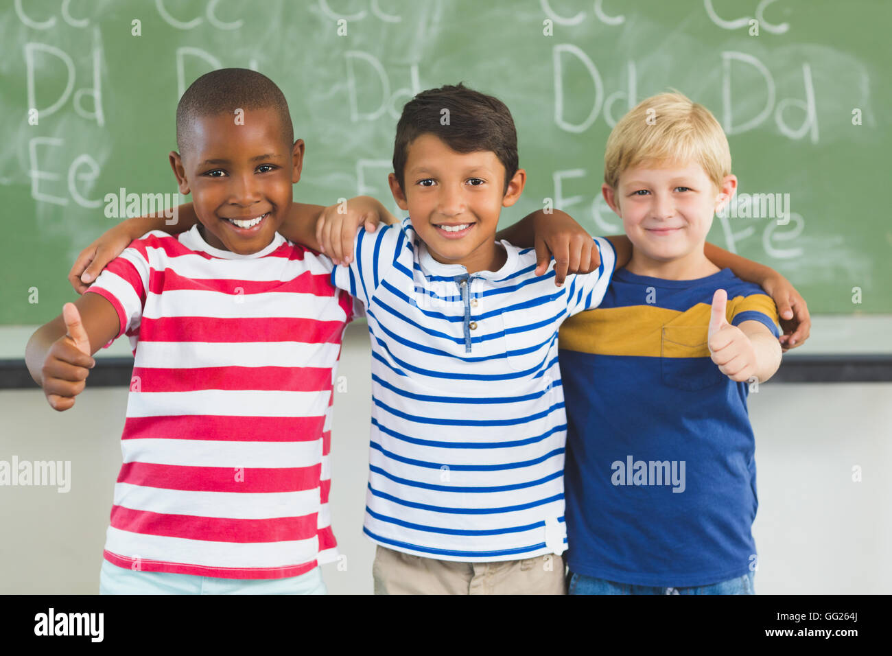 Smiling kids showing thumbs up in classroom Stock Photo - Alamy