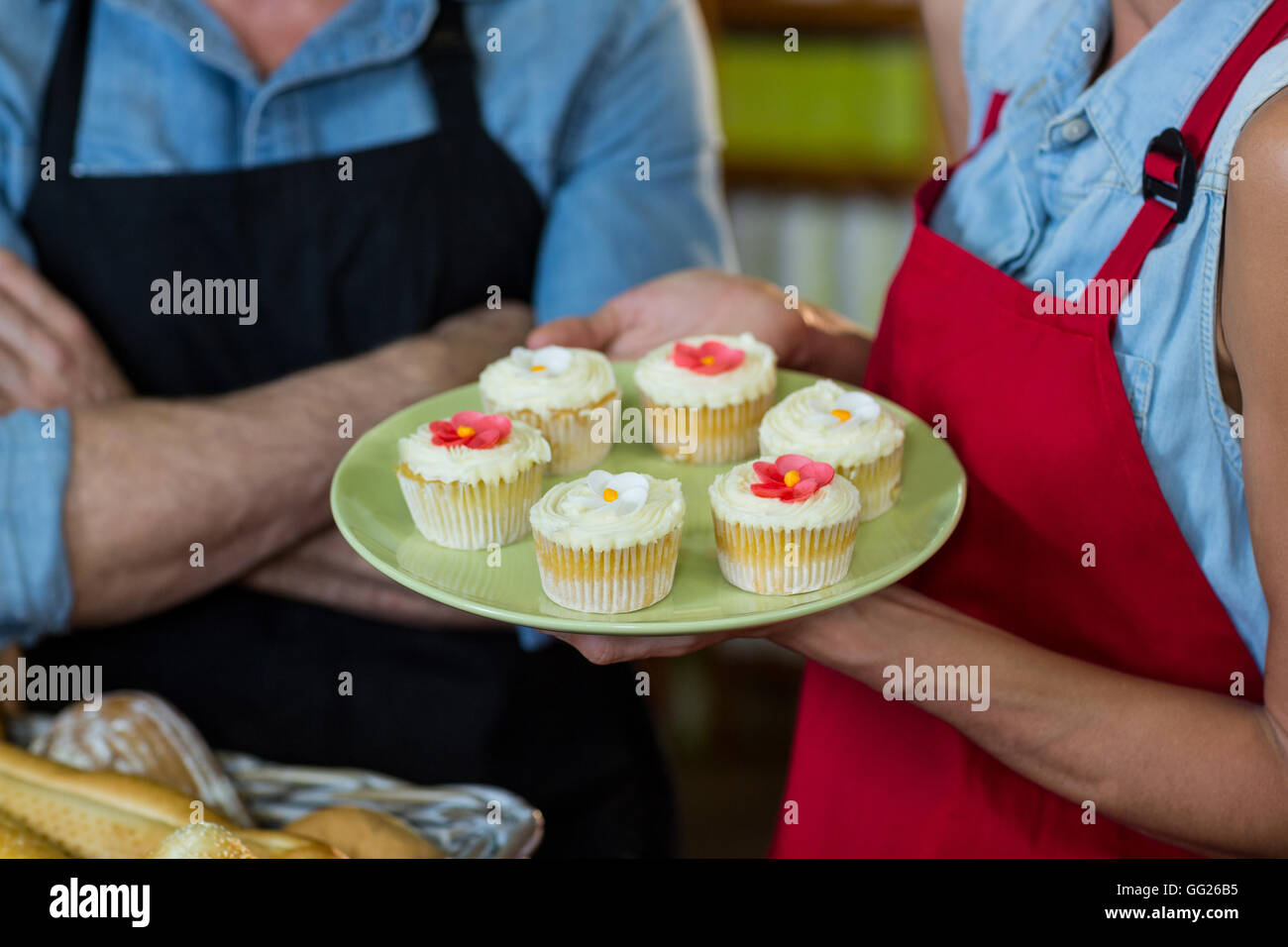 Mid section of female staff holding a plate of cupcakes Stock Photo - Alamy