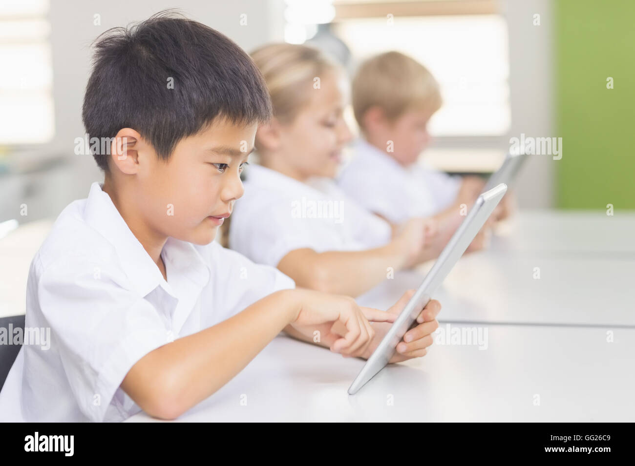 Kids using digital tablet in classroom Stock Photo - Alamy