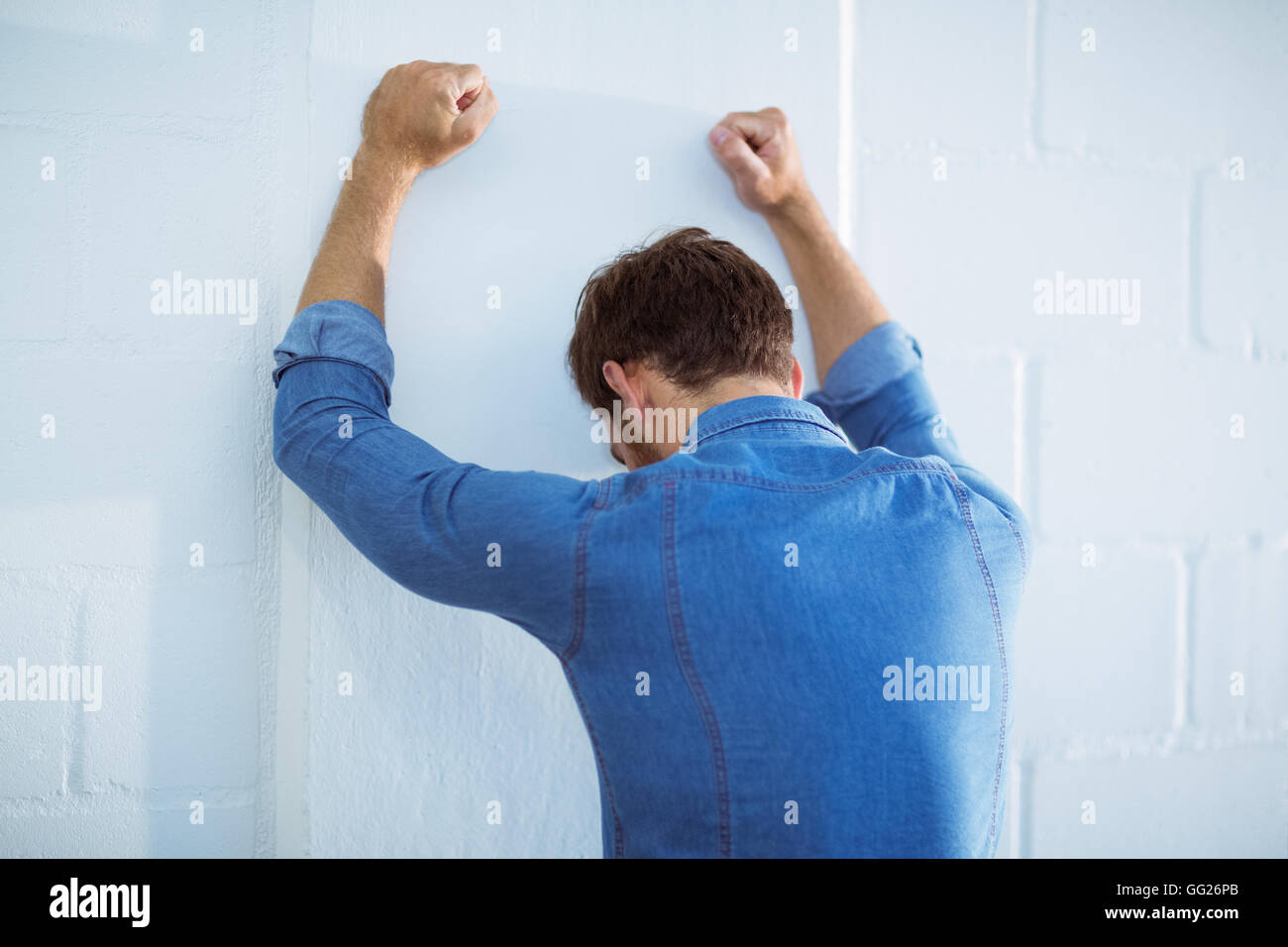 Tired businessman leaning on wall Stock Photo - Alamy