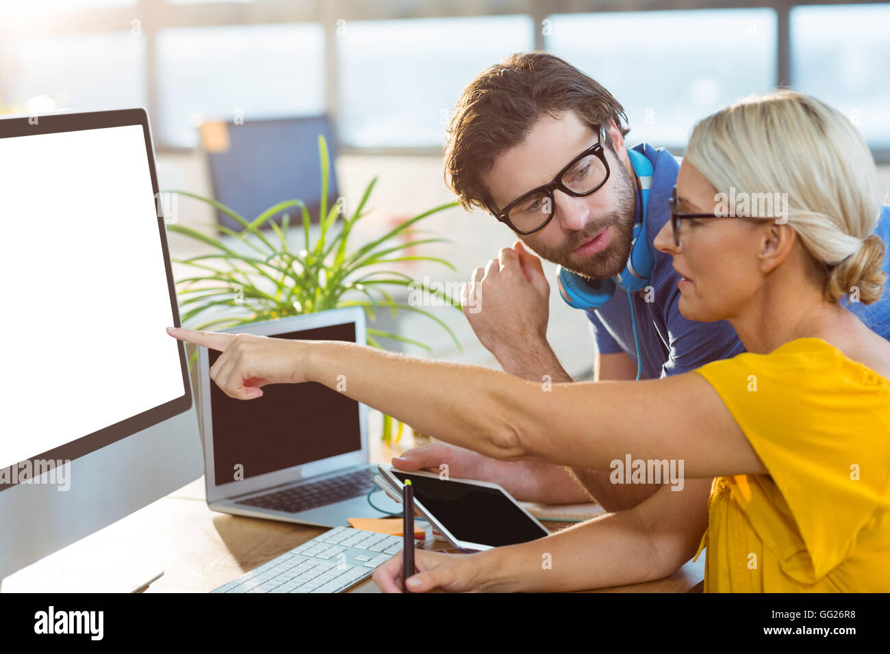 Graphic designers interacting while working on computer Stock Photo - Alamy