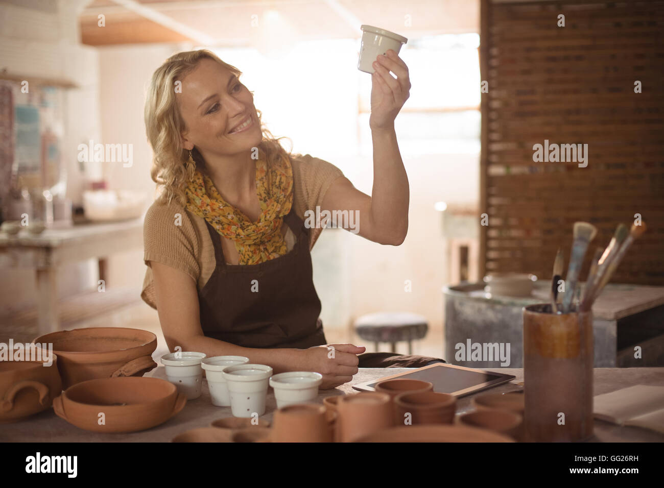 Beautiful female potter checking pot Stock Photo - Alamy