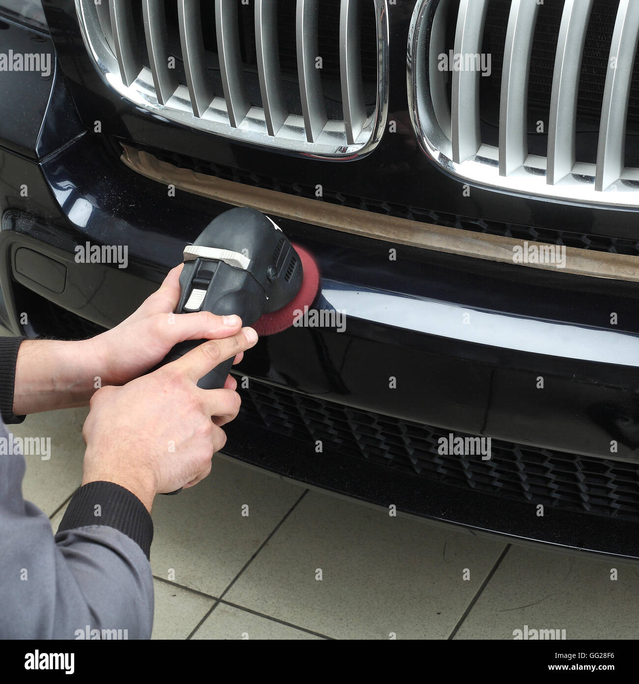 The worker polishes a bumper car cowl with the electric tool. Close up ...