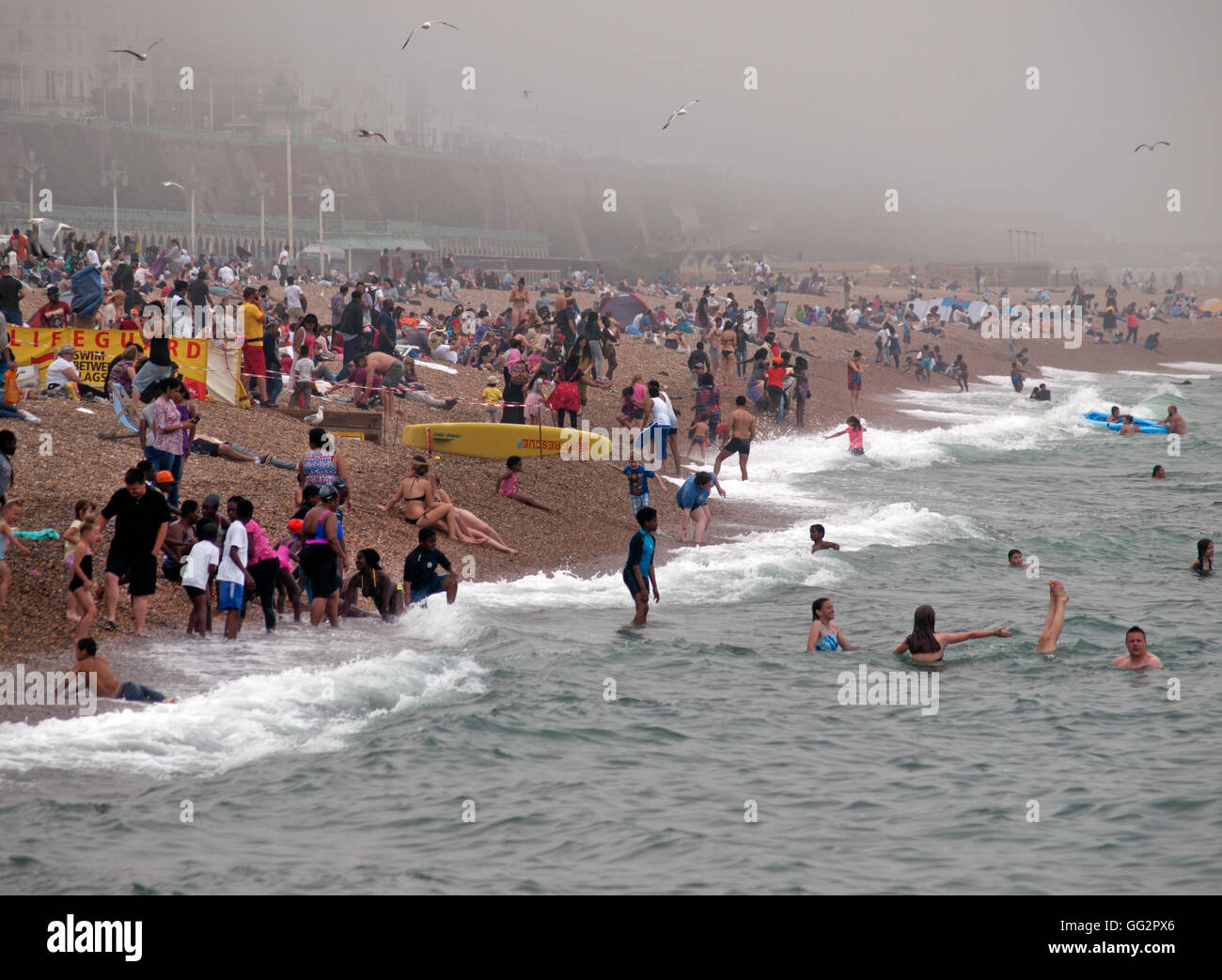 Lots of people having fun in the sea and on the beach in Brighton Stock ...