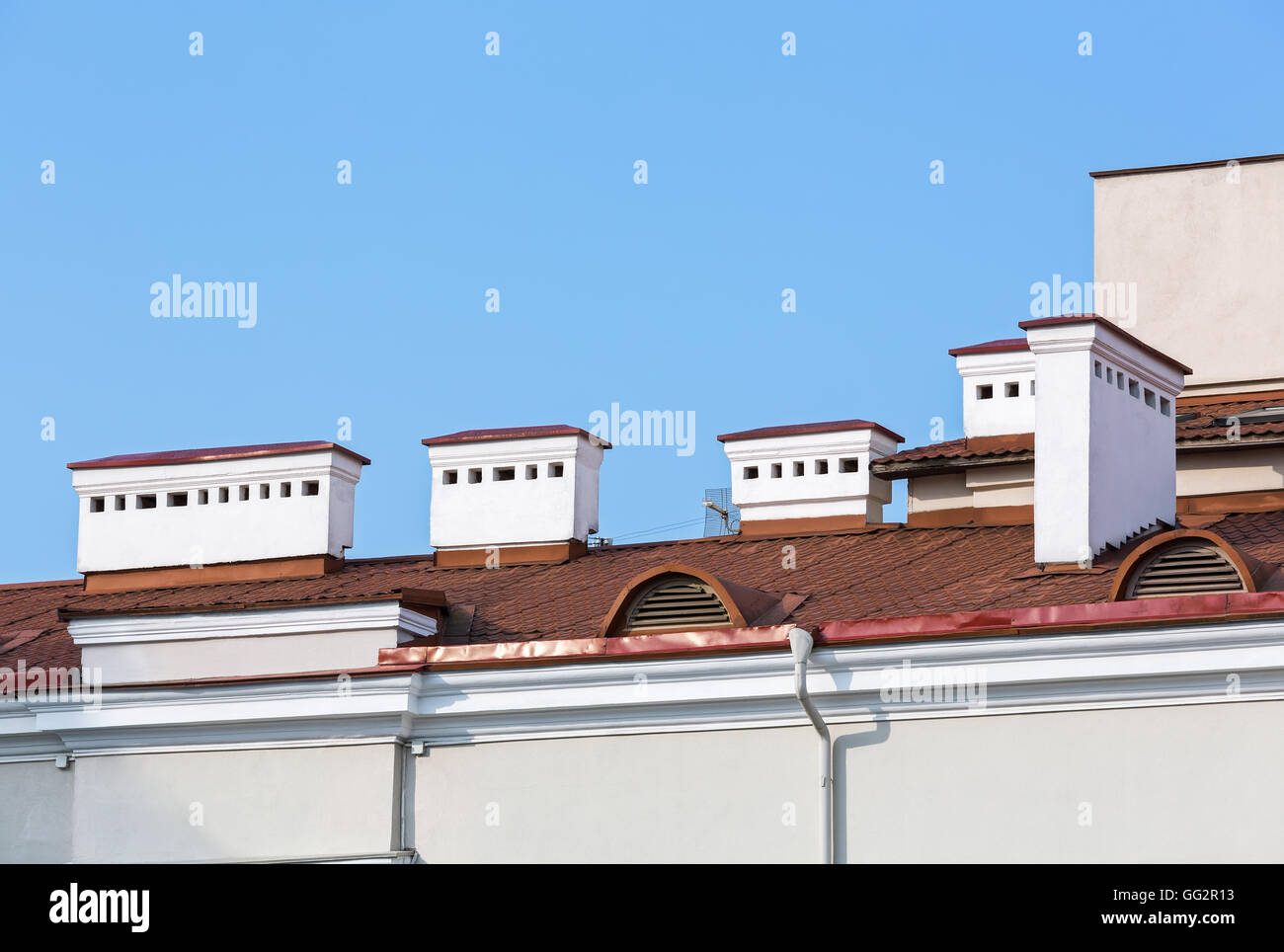Chimneys on building rooftop against blue sky background Stock Photo ...