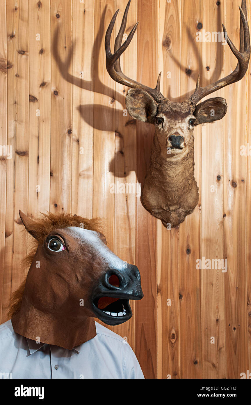A person wearing a horse mask in front of a deer head Stock Photo - Alamy