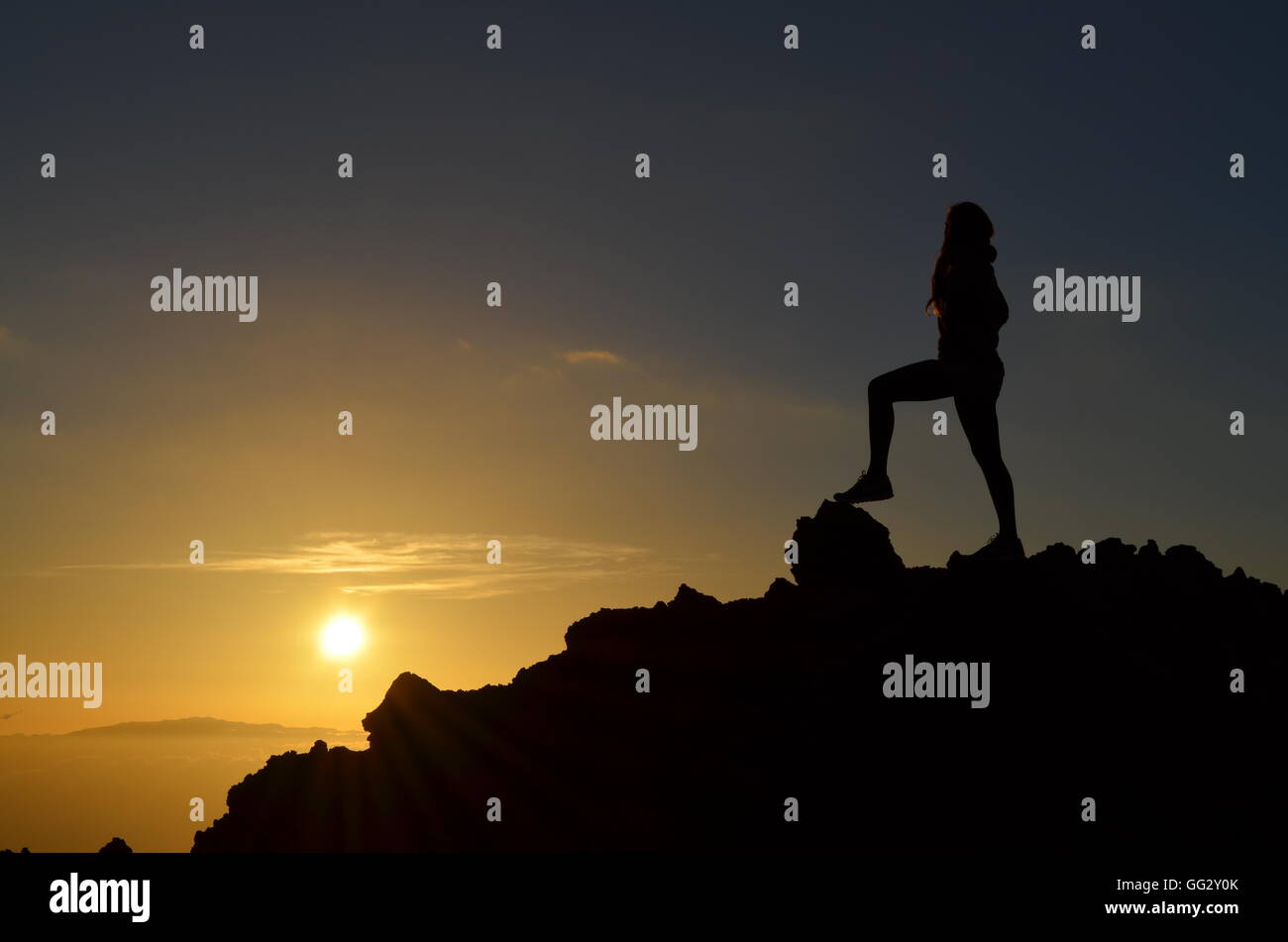 Success and Freedom - young woman stands on a mountain during sunset ...