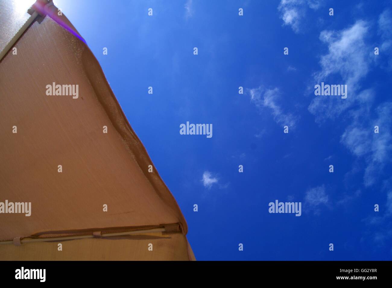 Parasol open with blue skies and the sun shining Stock Photo - Alamy