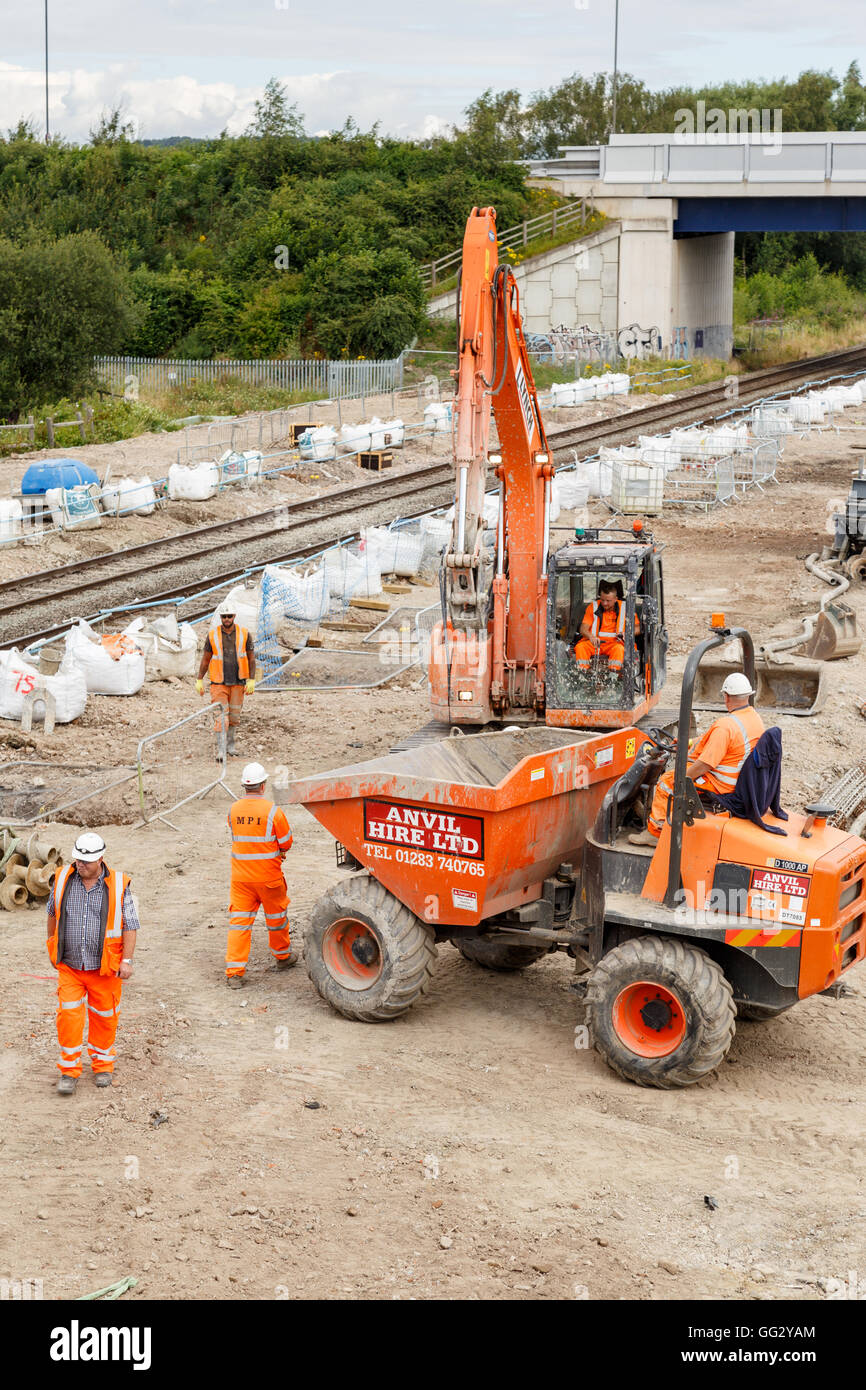 Construction workers on site next to a section of railway track. In ...