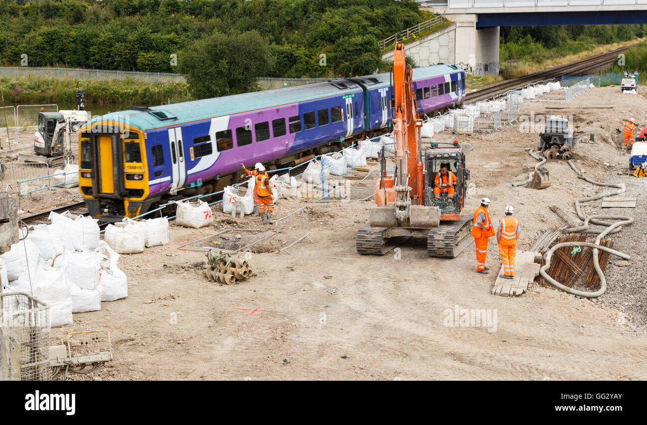 A train passes by construction workers on site next to a section of ...