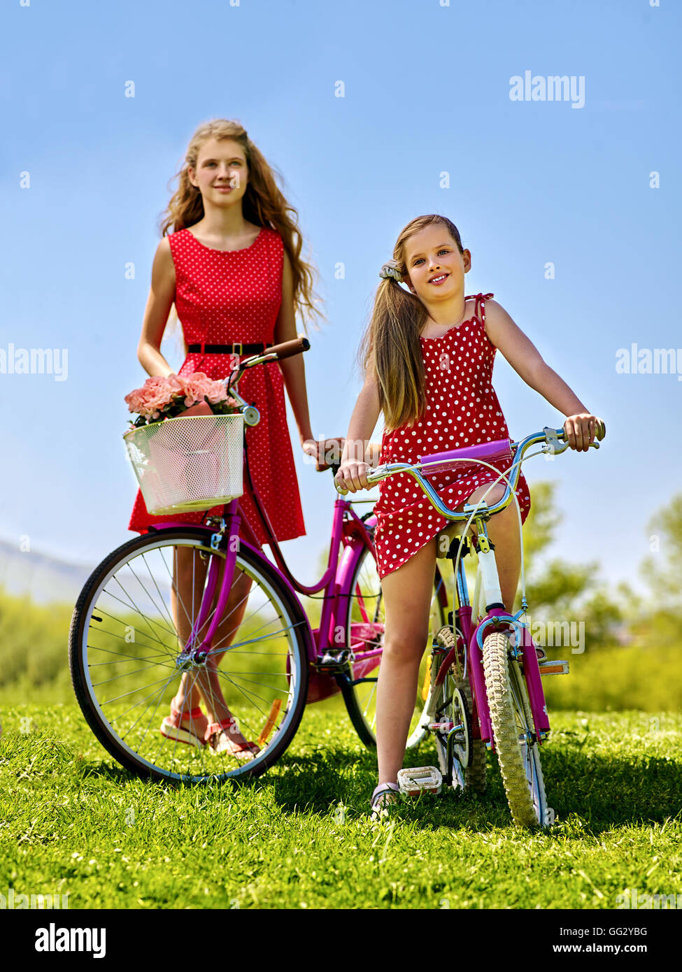 Girl wearing red dress rides bicycle into summer park Stock Photo - Alamy