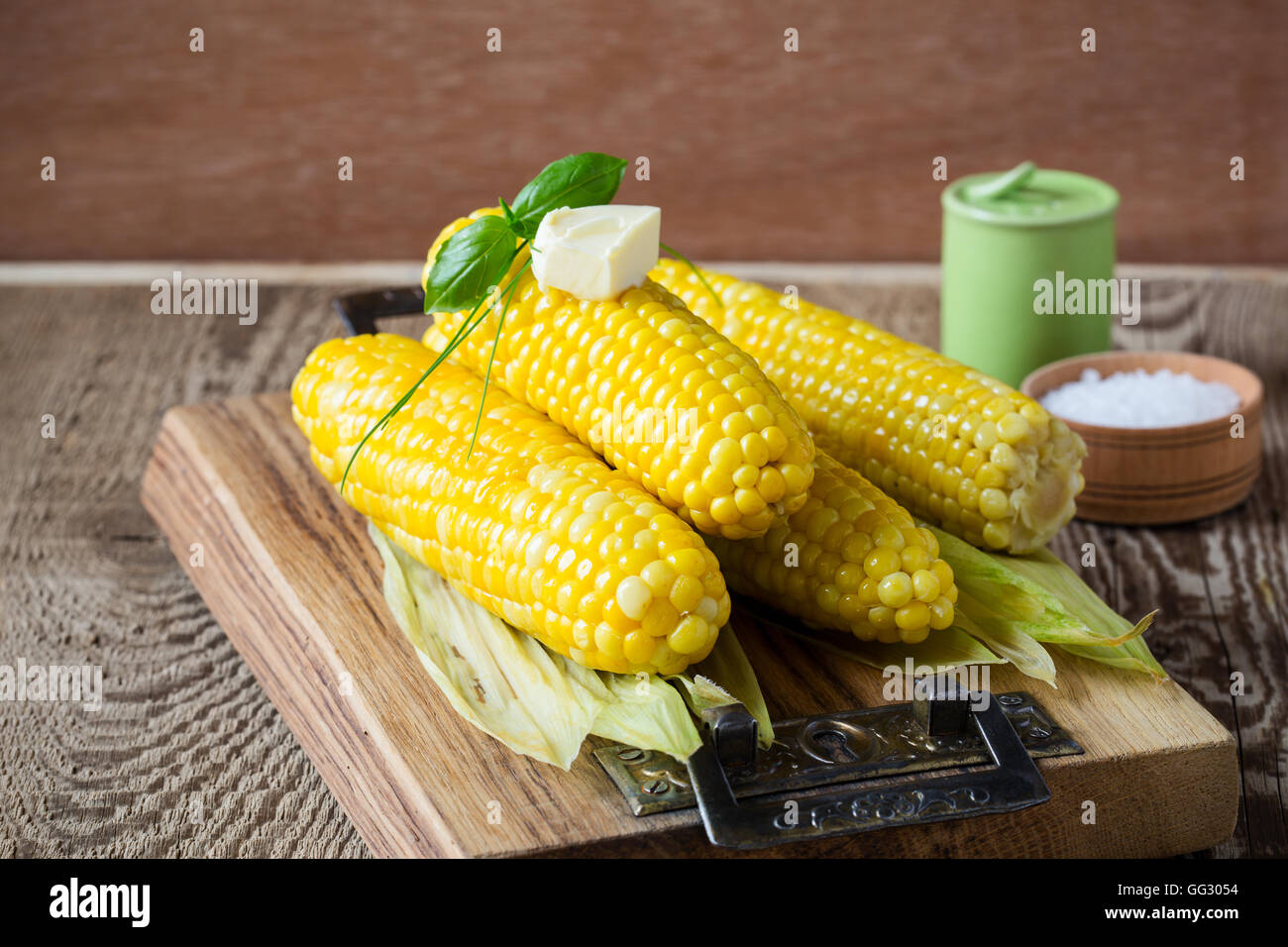Homemade boiled corn on cob with butter and salt on rustic wooden table ...