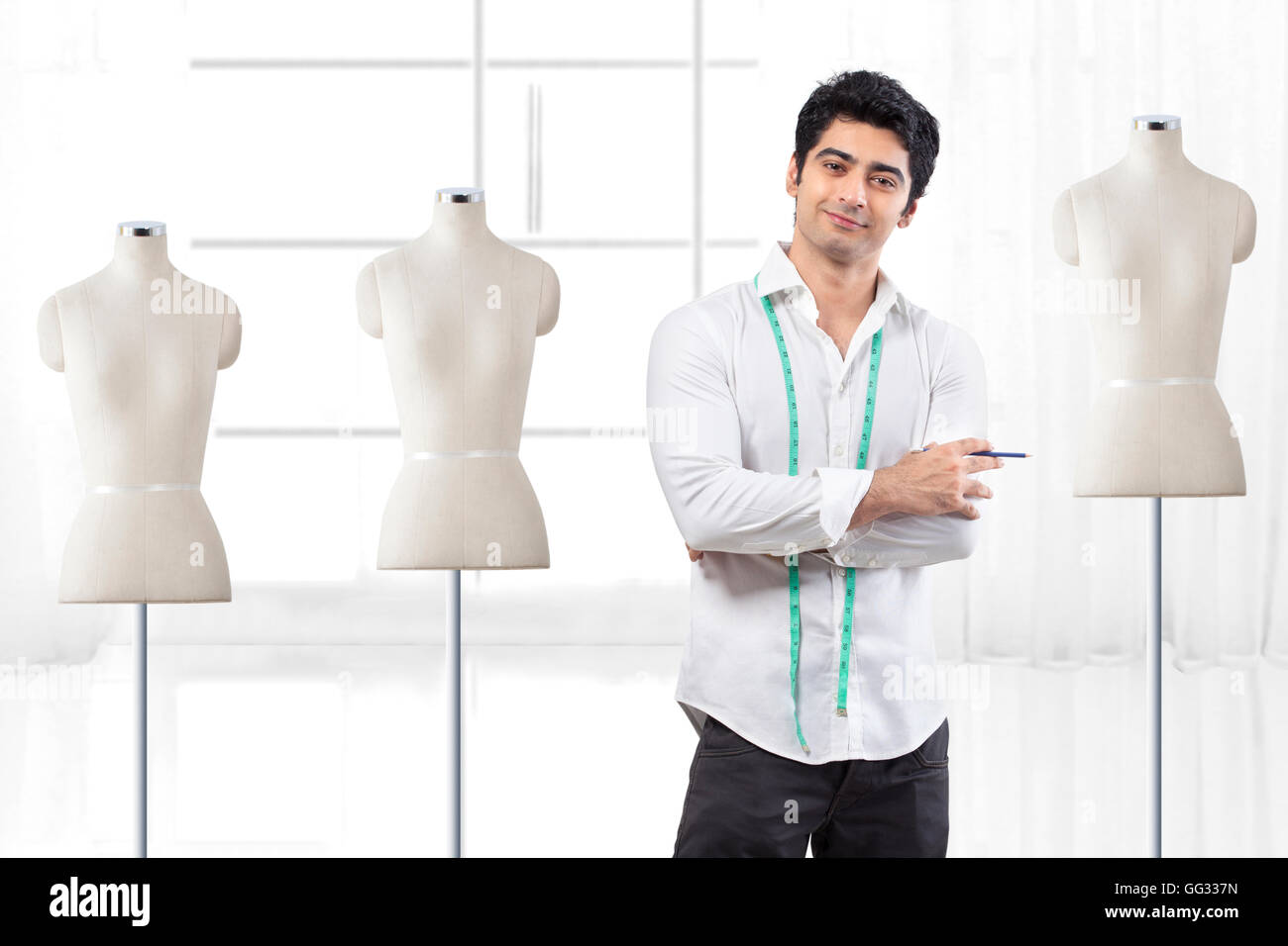 Handsome male fashion designer standing by mannequin at studio Stock ...