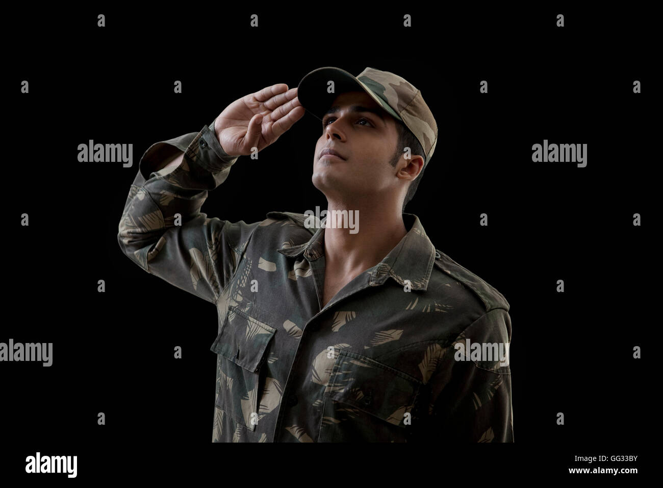 Soldier saluting while looking up against black background Stock Photo ...