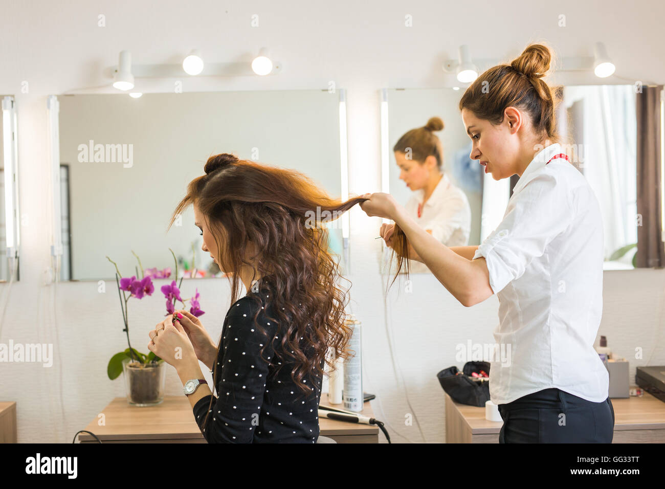 working day inside the beauty salon. Hairdresser makes hair styling ...