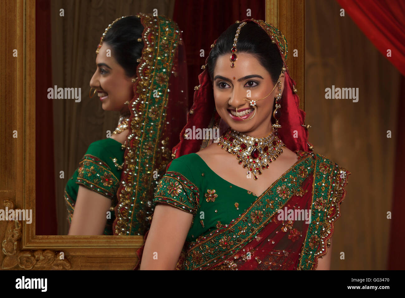 Beautiful young Indian bride standing in front of mirror Stock Photo ...