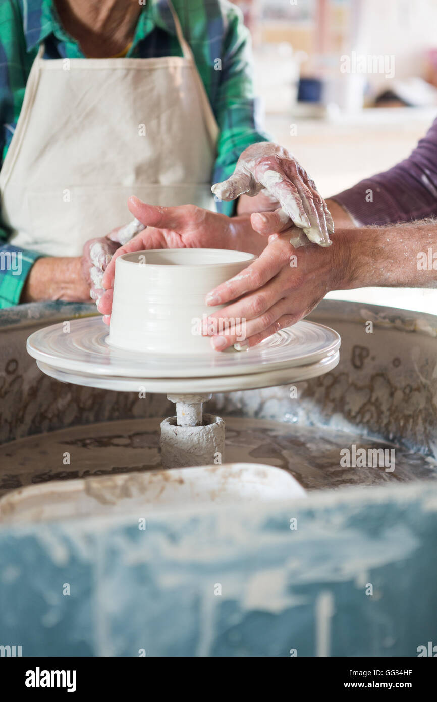 Male potter assisting female potter while making pot Stock Photo - Alamy