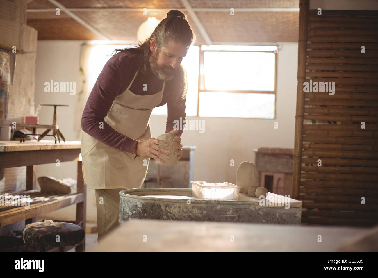 Male potter putting clay pottery wheel in pottery workshop Stock Photo ...