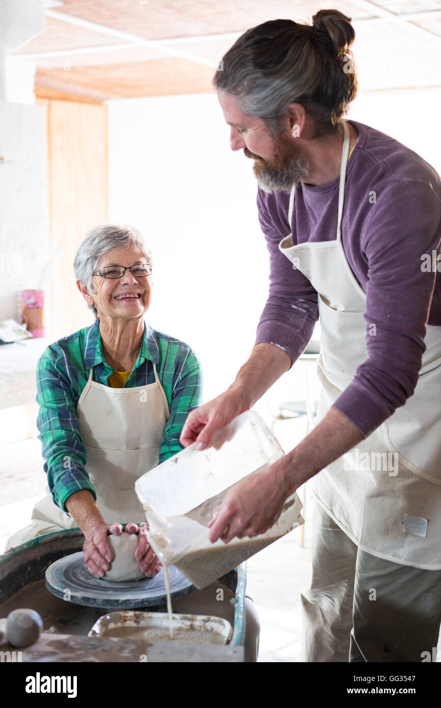 Male potter assisting female potter while making pot Stock Photo - Alamy