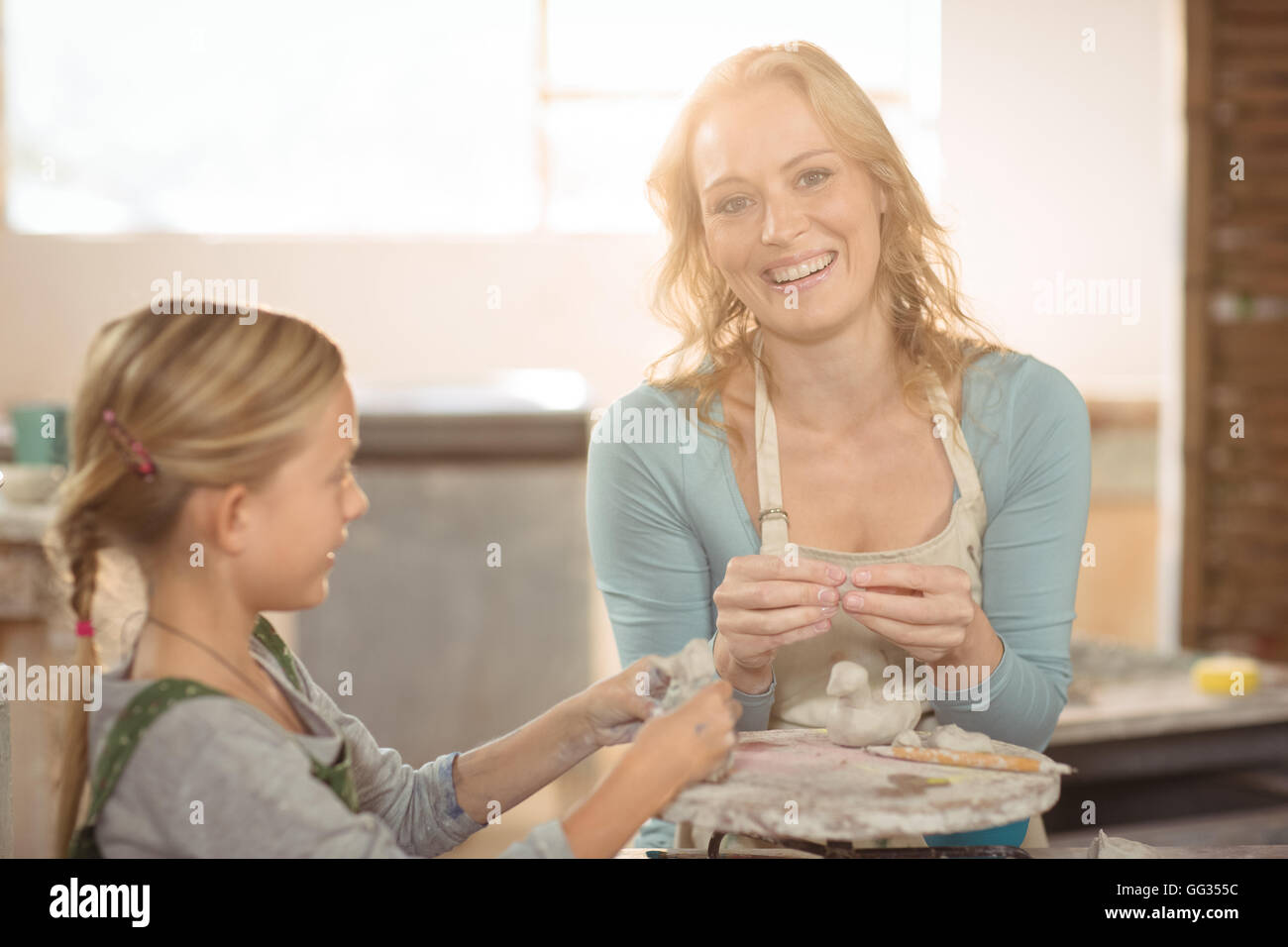 Smiling female potter assisting girls Stock Photo - Alamy