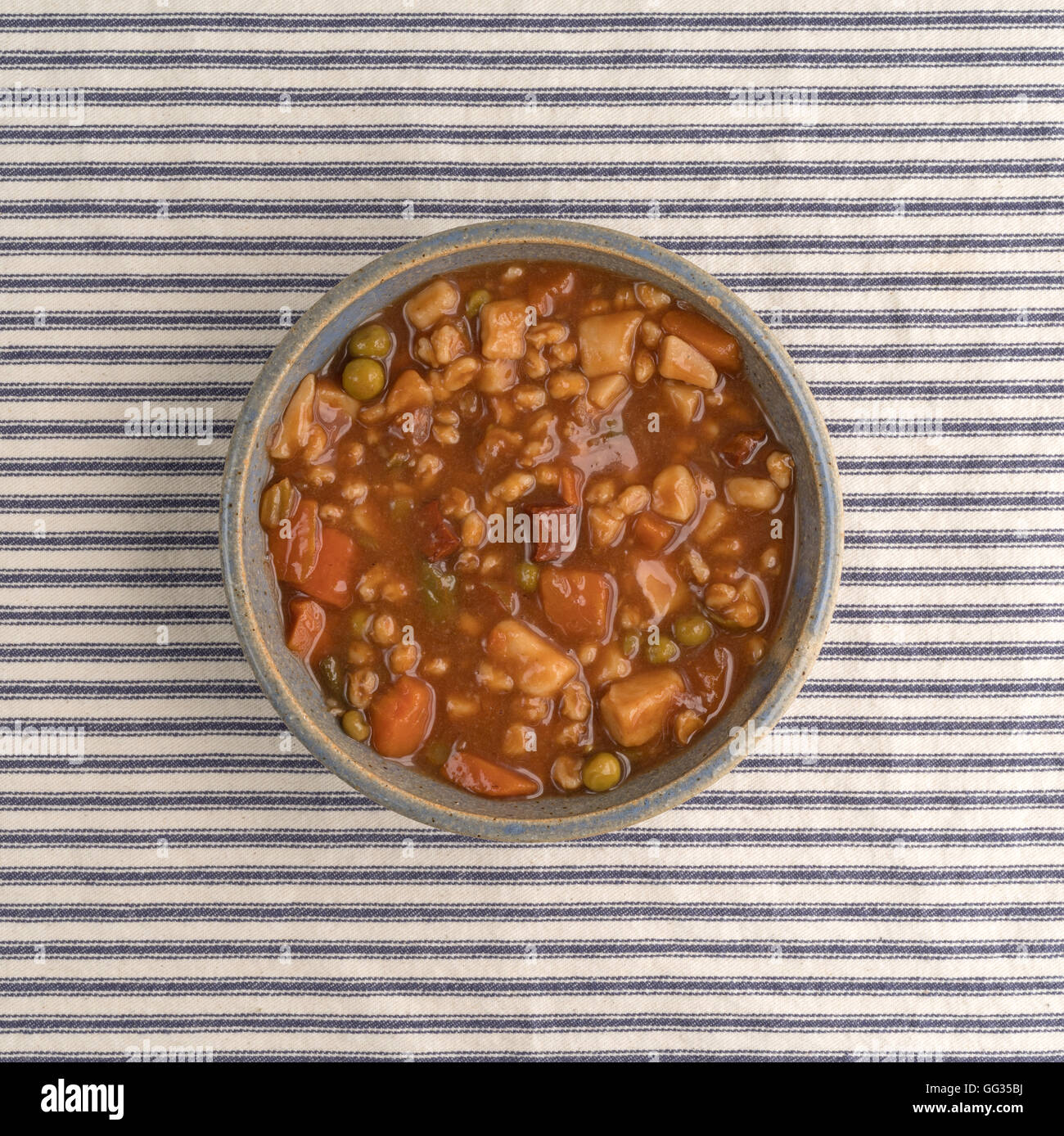 Top view of a serving of beef stew in an old bowl atop a striped ...