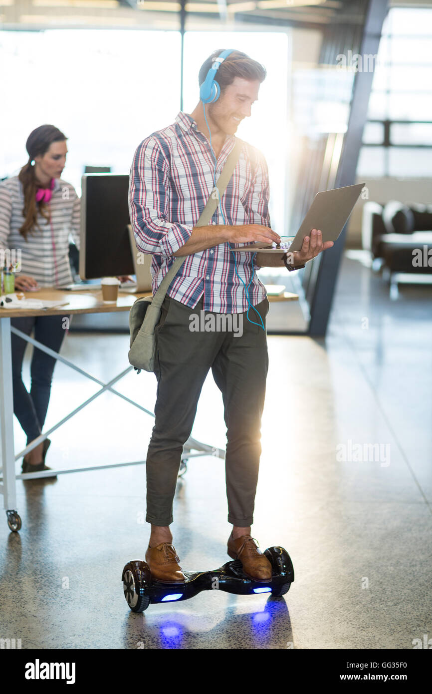 Smiling man standing on hoverboard and using laptop Stock Photo - Alamy
