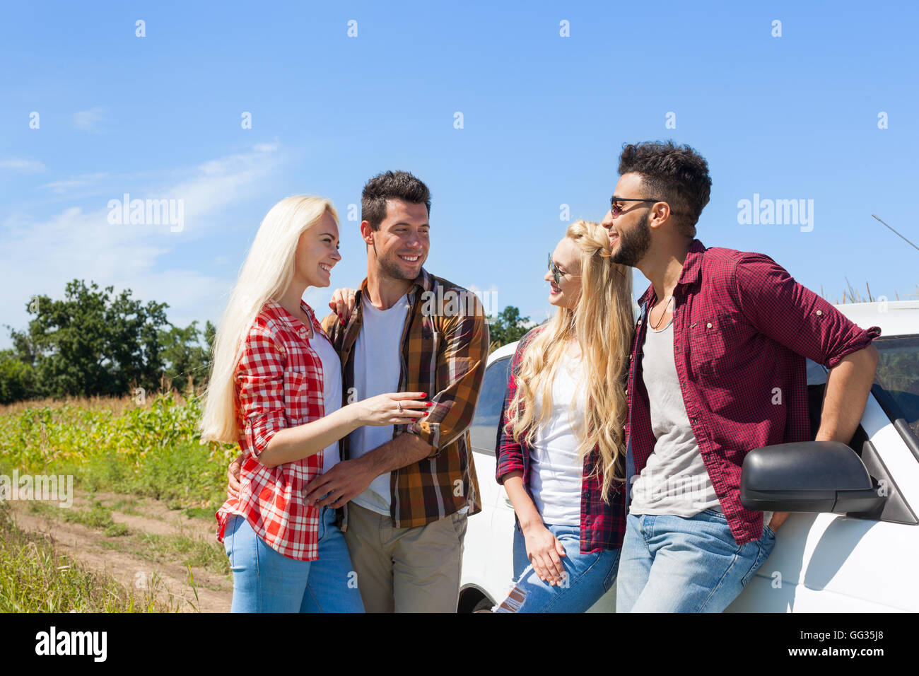 Friends talking chatting outdoor countryside people smile near car ...